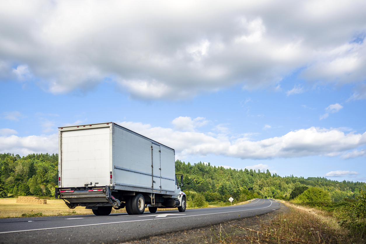 Big rig semi truck with long box trailer driving on the winding road ...